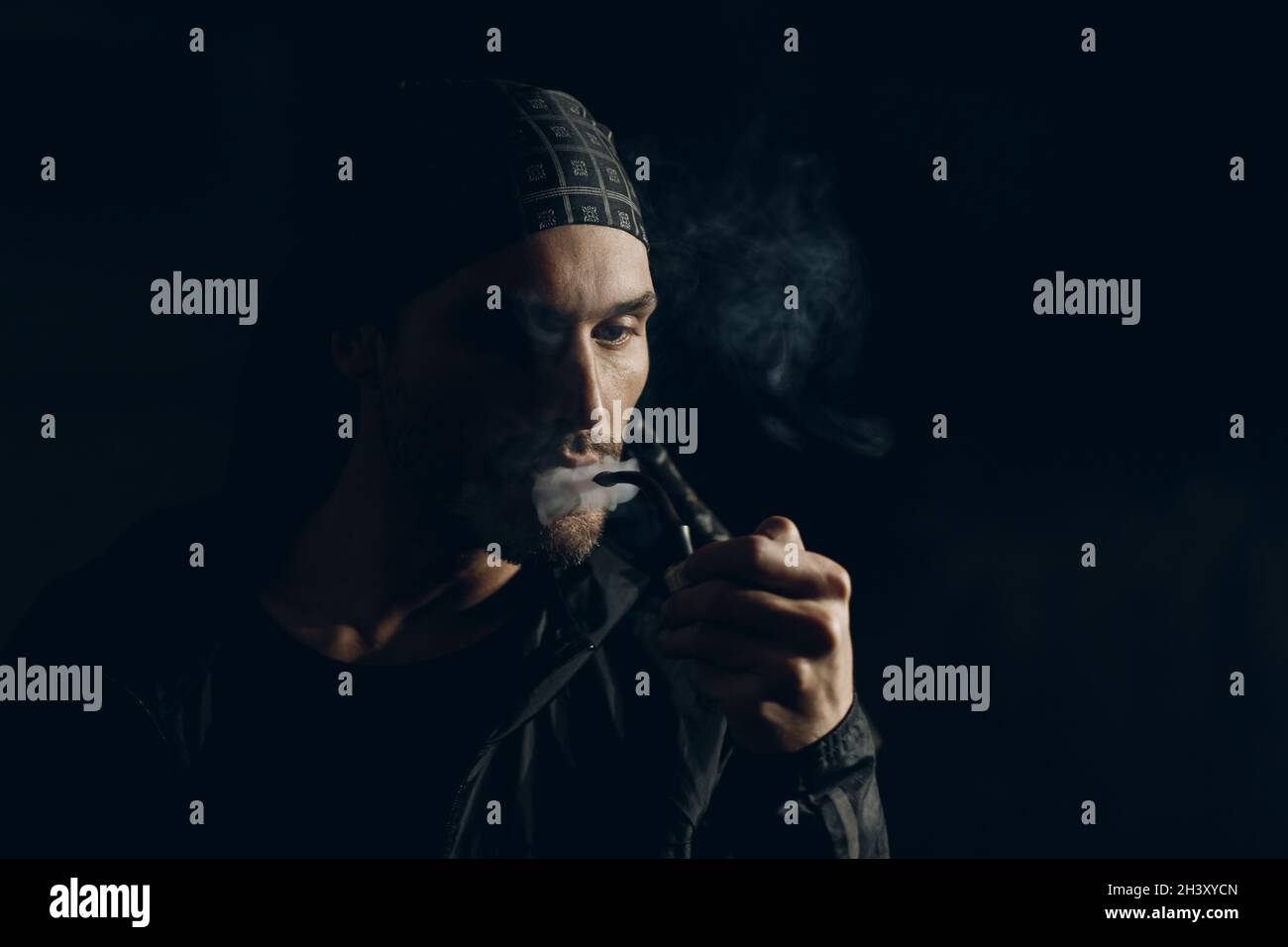 Man smoking a pipe on dark background. Back lit profile portrait Stock ...