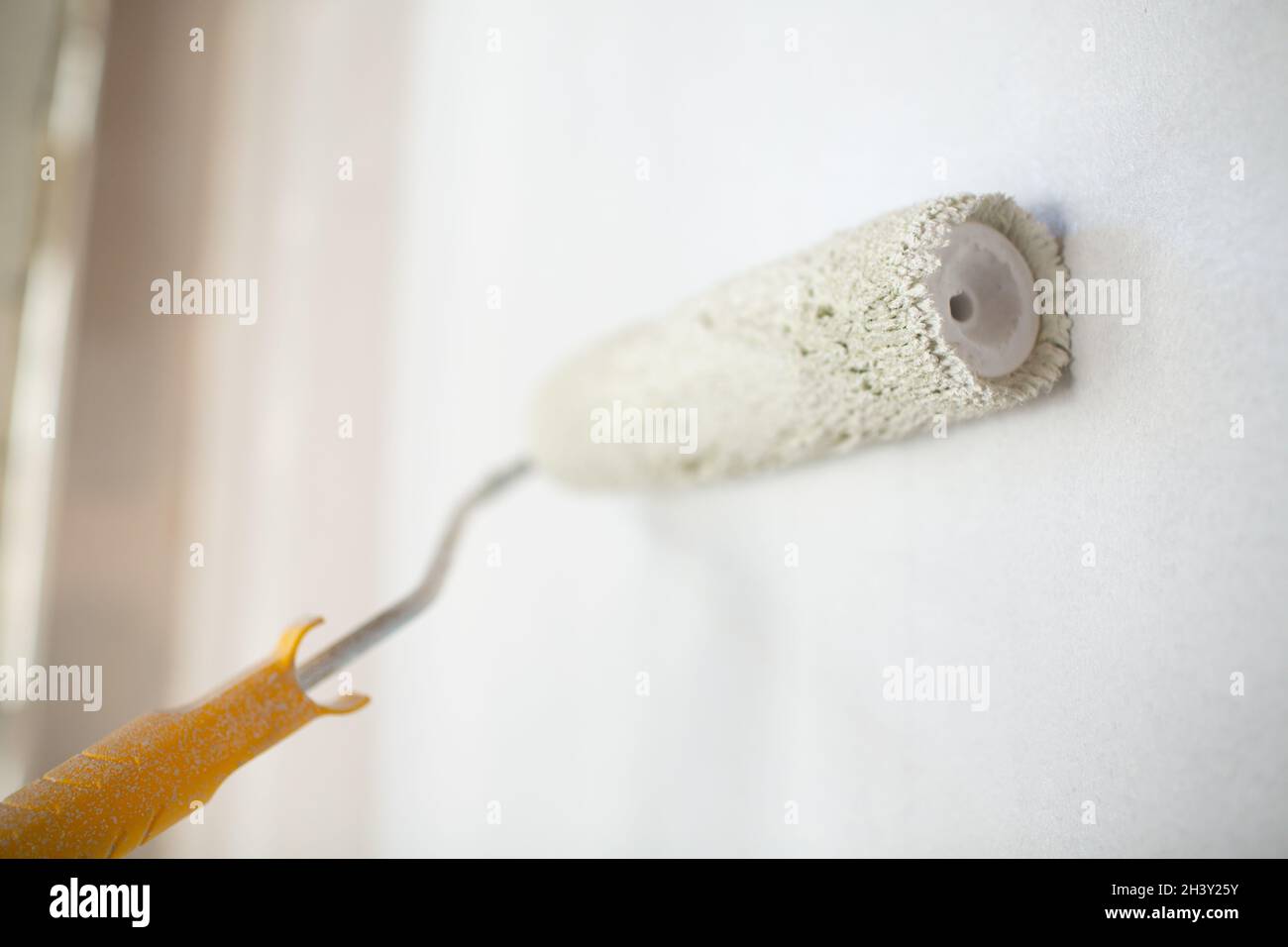White paint roller in hand with drywall wall Stock Photo - Alamy