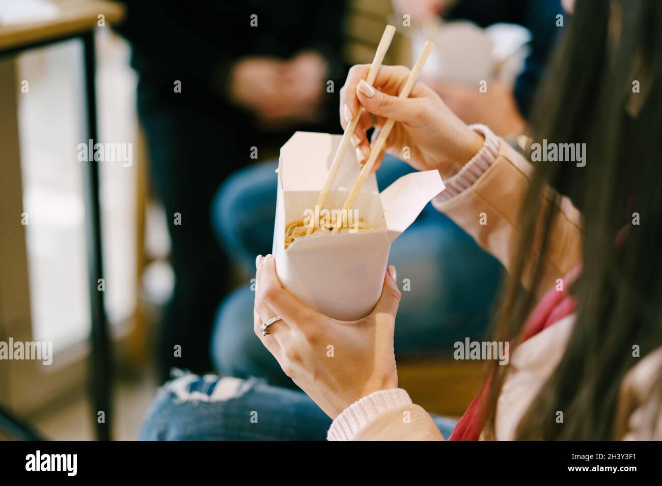 Beautiful woman are eating asian fast food from takeaway box. Delicious ...