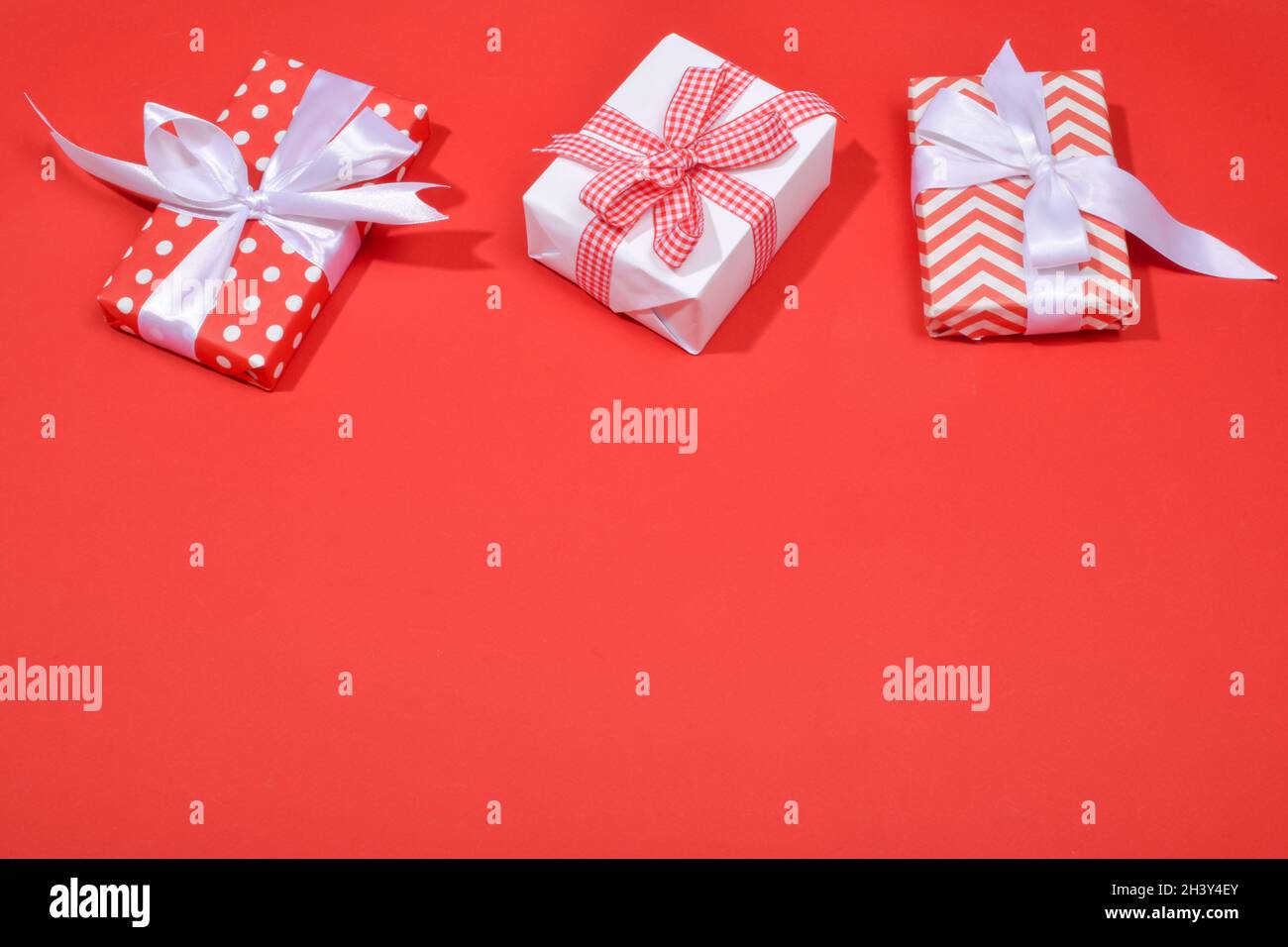 Top view of a red gift box with a white ribbon on a red background ...