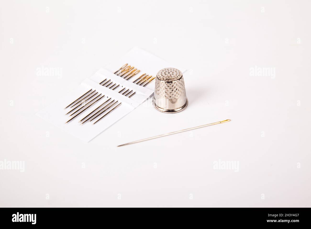 Set of steel sewing needle and silver thimble for sewing, isolated on ...