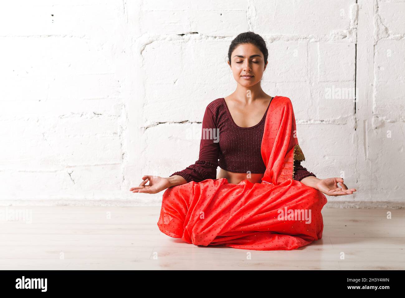 Young adult indian woman in sari meditating yoga lotus pose zen like ...