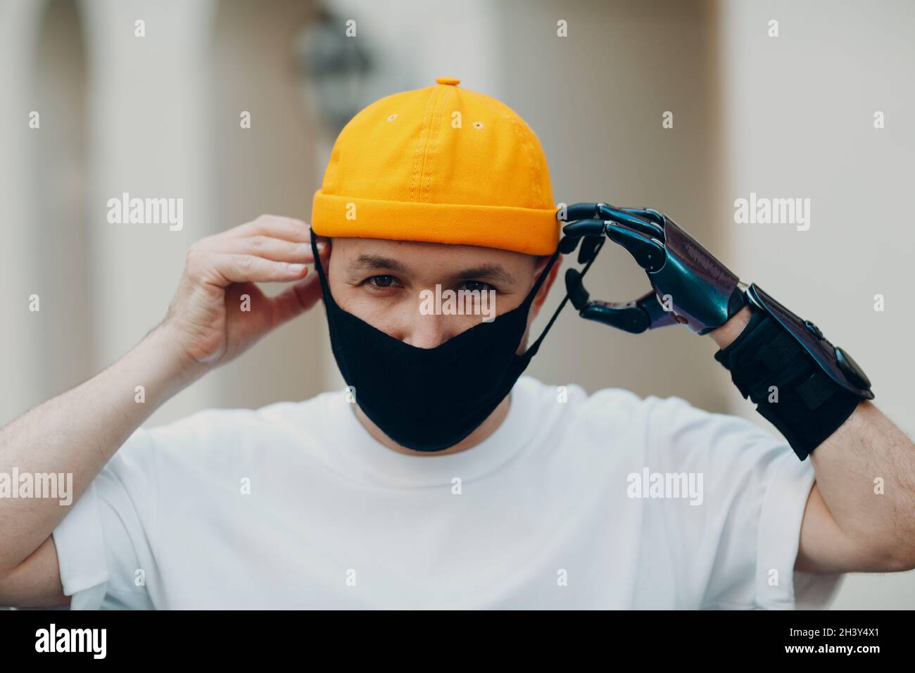 Young disabled man put on medical protective face mask with artificial ...