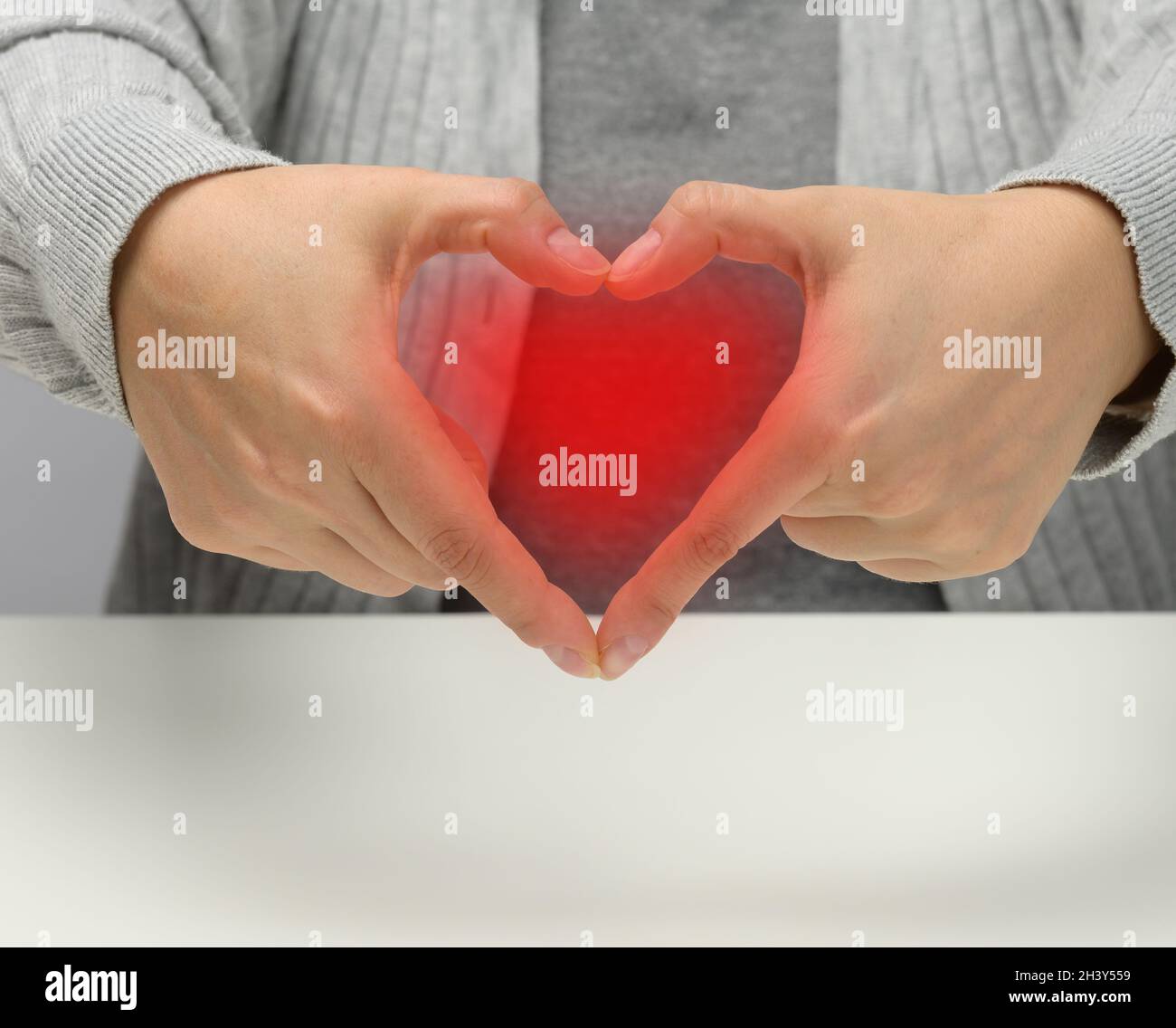 Two female hands folded in the shape of a heart on a white background ...
