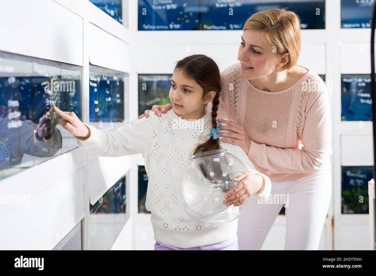Cute girl with her mother customer buying tropical fish Stock Photo - Alamy