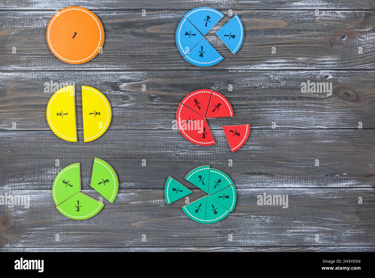 Multicolored fractions, blocks, notebook on a gray wooden table. Back ...