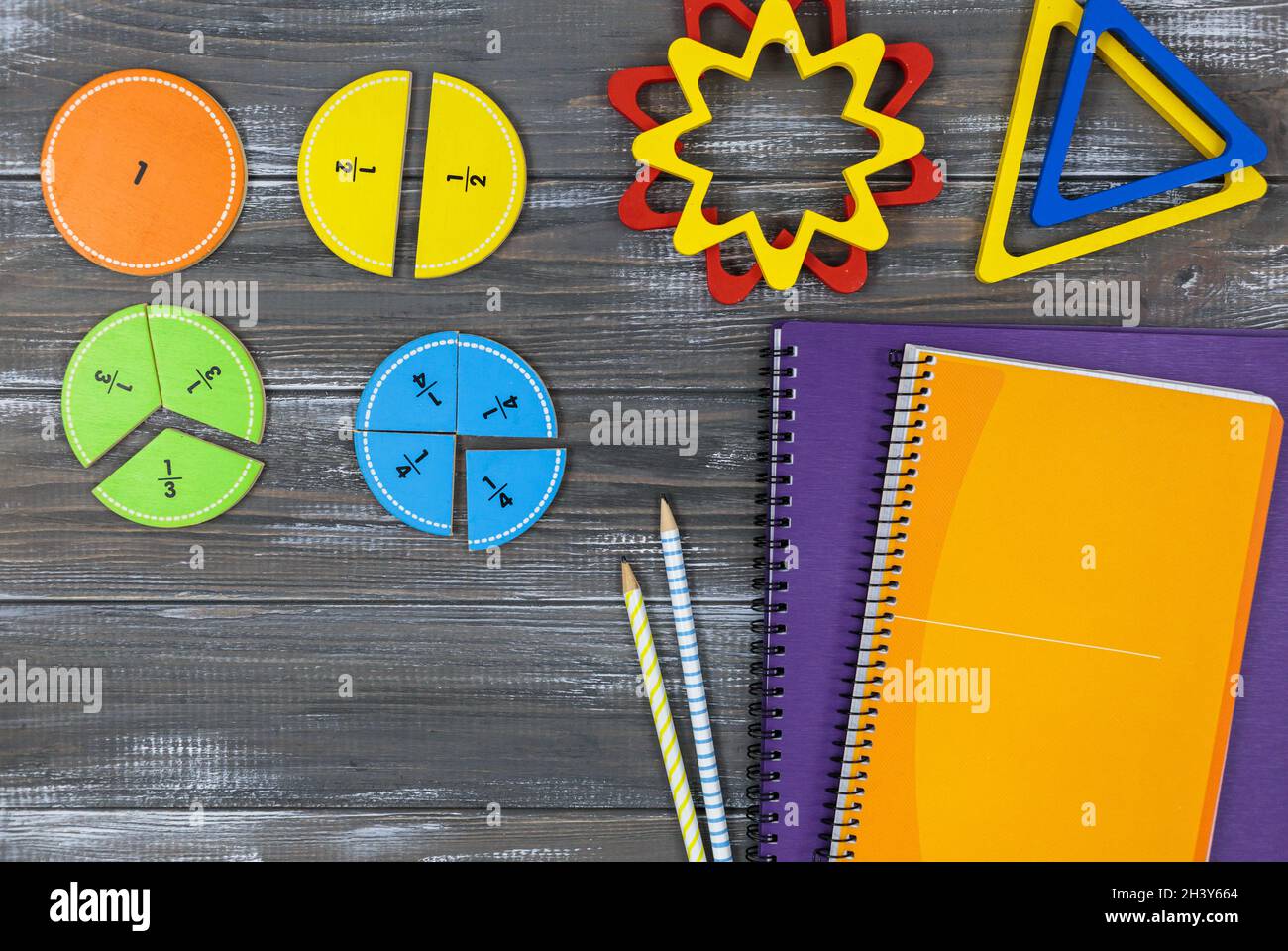 Multicolored fractions, blocks, notebook on a gray wooden table. Back ...