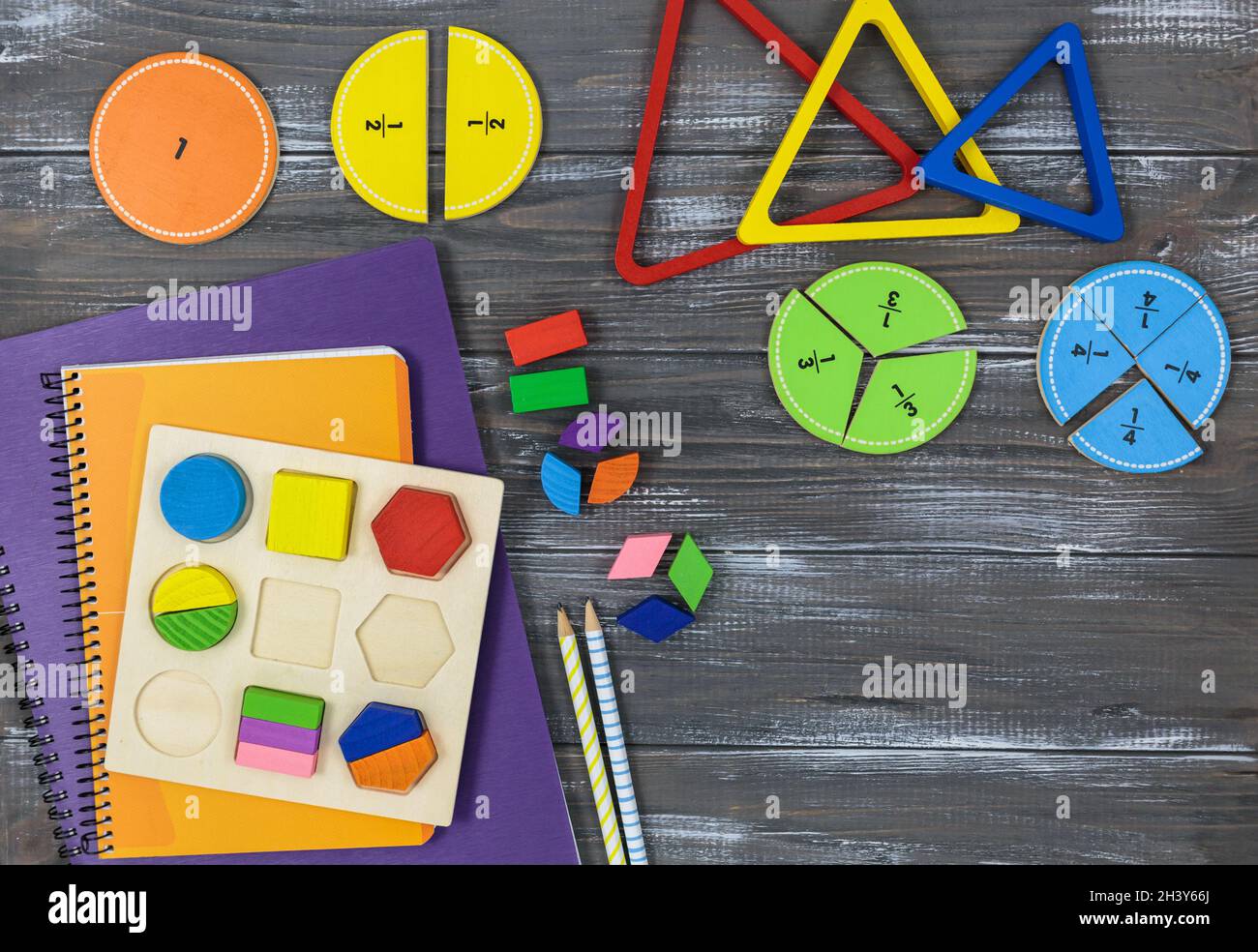 Multicolored fractions, blocks, notebook on a gray wooden table. Back ...