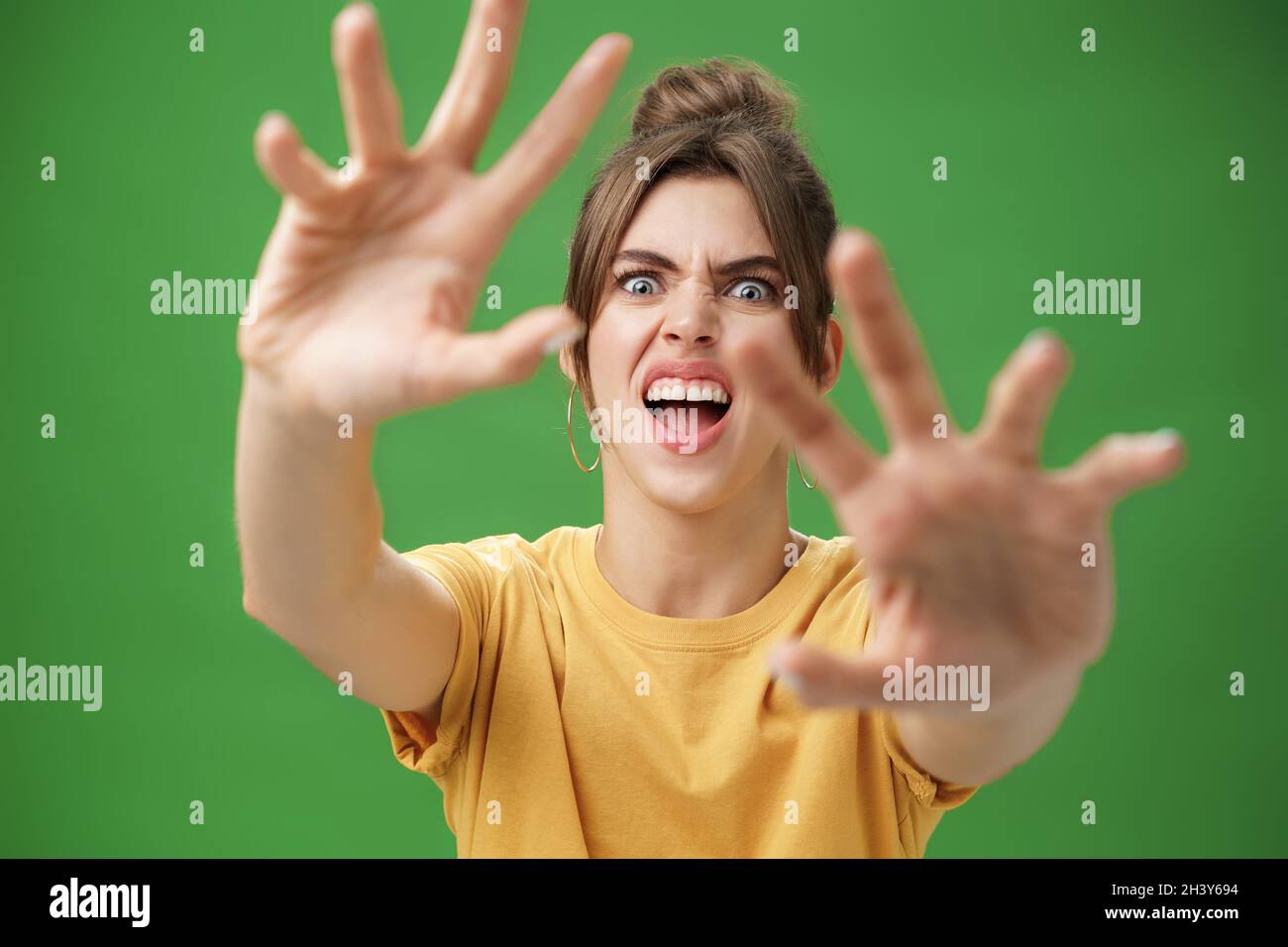 Funny emotive woman making fun face pulling hands forward to attack of ...