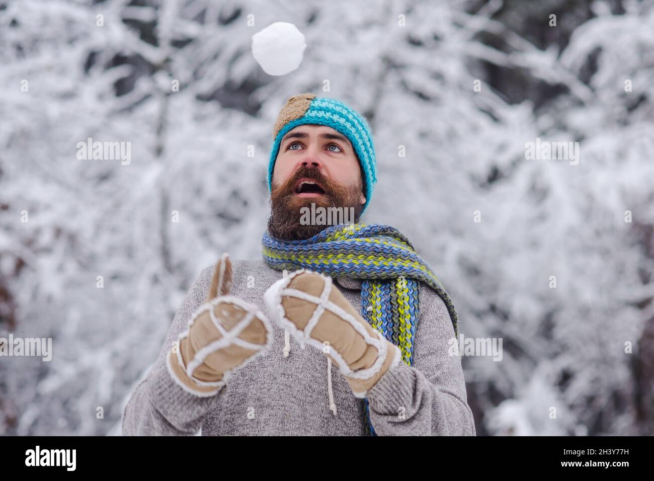 Bearded hipster play with snowball in snowy forest. Winter man in ...
