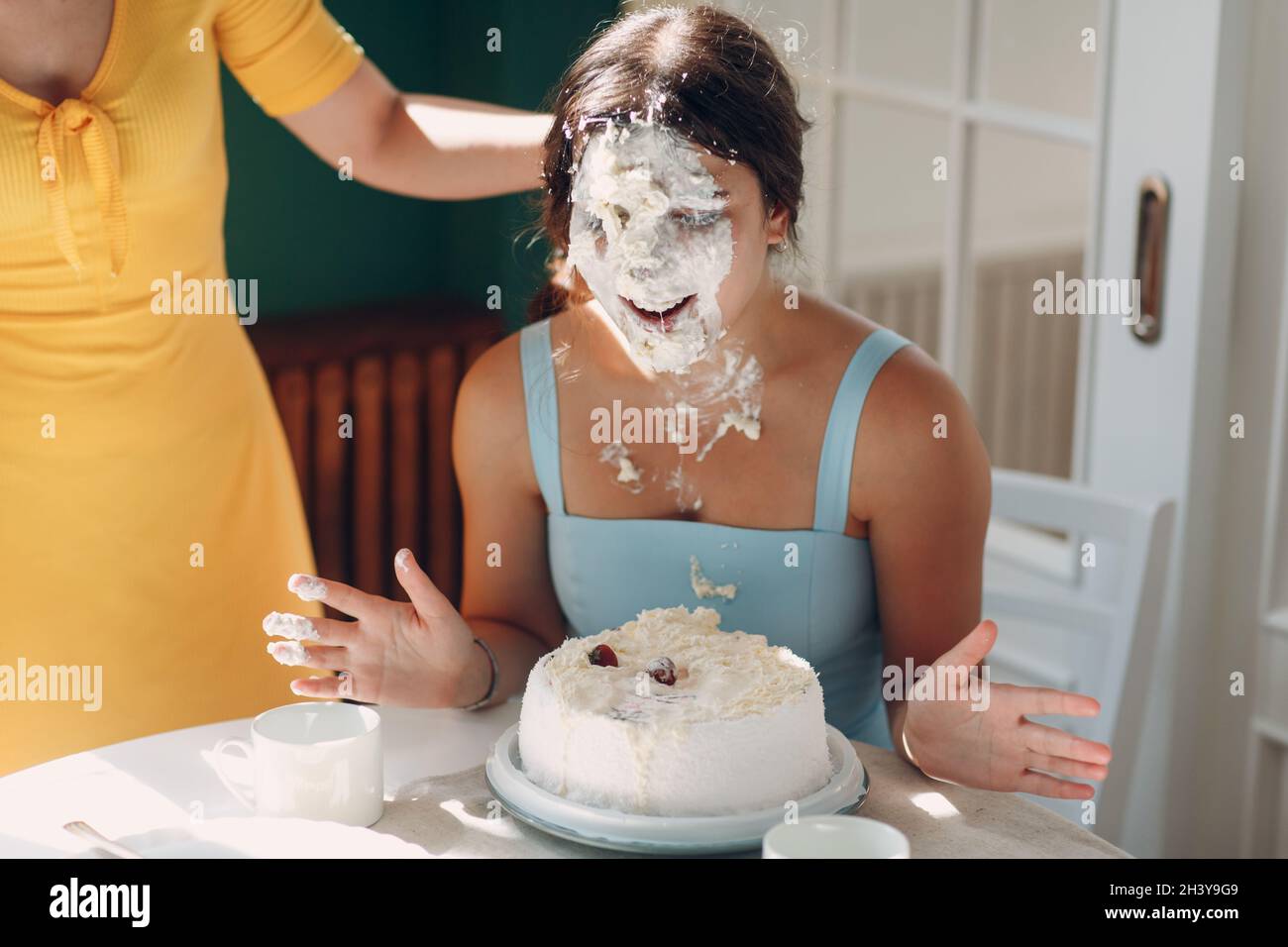 Young woman dips face in white cake with cream. Happy birthday concept ...