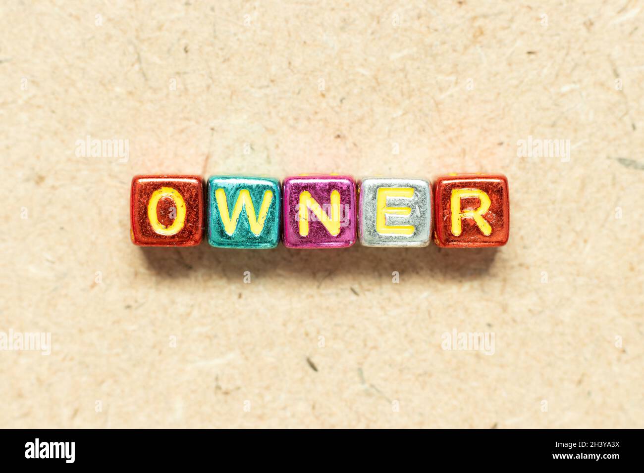 Metallic color alphabet letter block in word owner on wood background ...