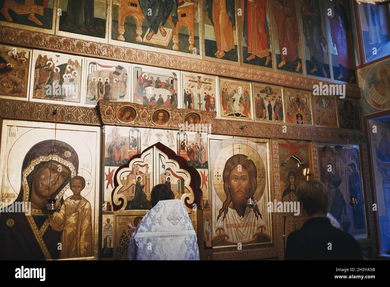 Orthodox Christian priest and parishioner praying at icons in the ...