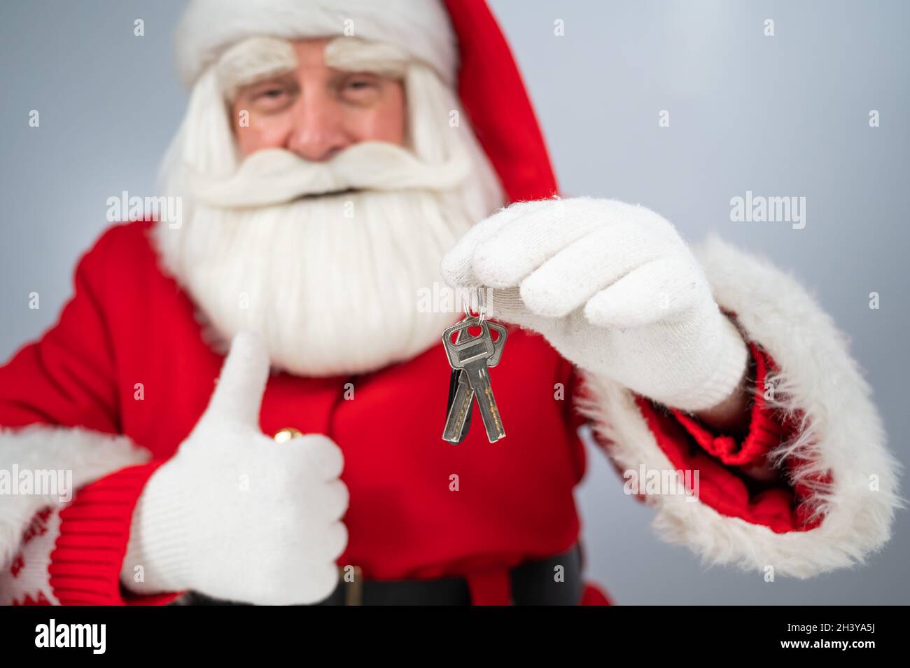 Santa Claus holds keys on a white background and thumb up. New home ...