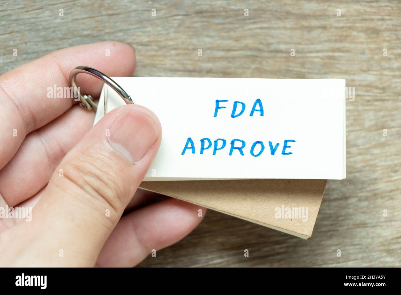 Man hold the flash card with handwriting word FDA approve on wood ...