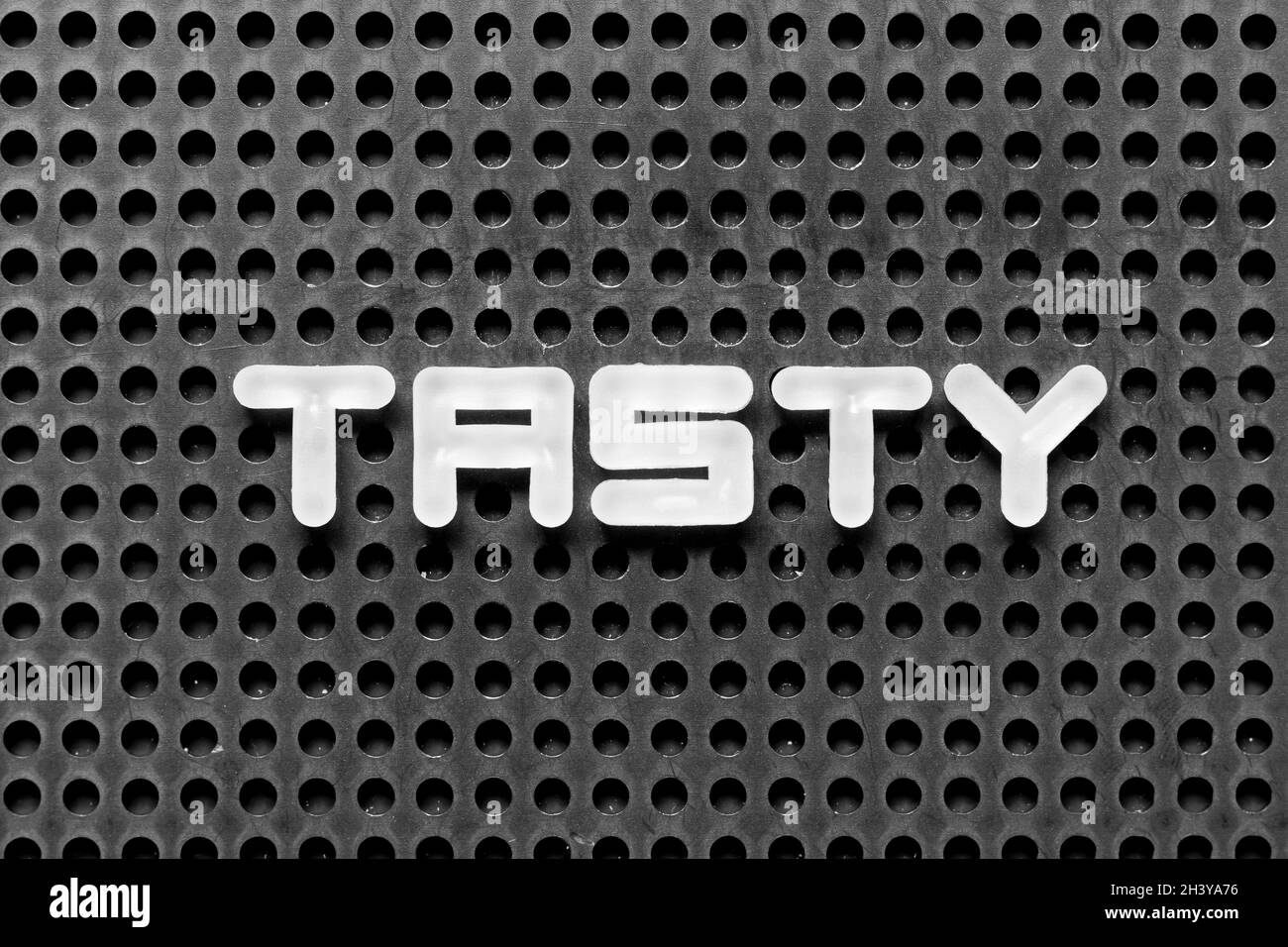White alphabet letter in word tasty on black pegboard background Stock ...