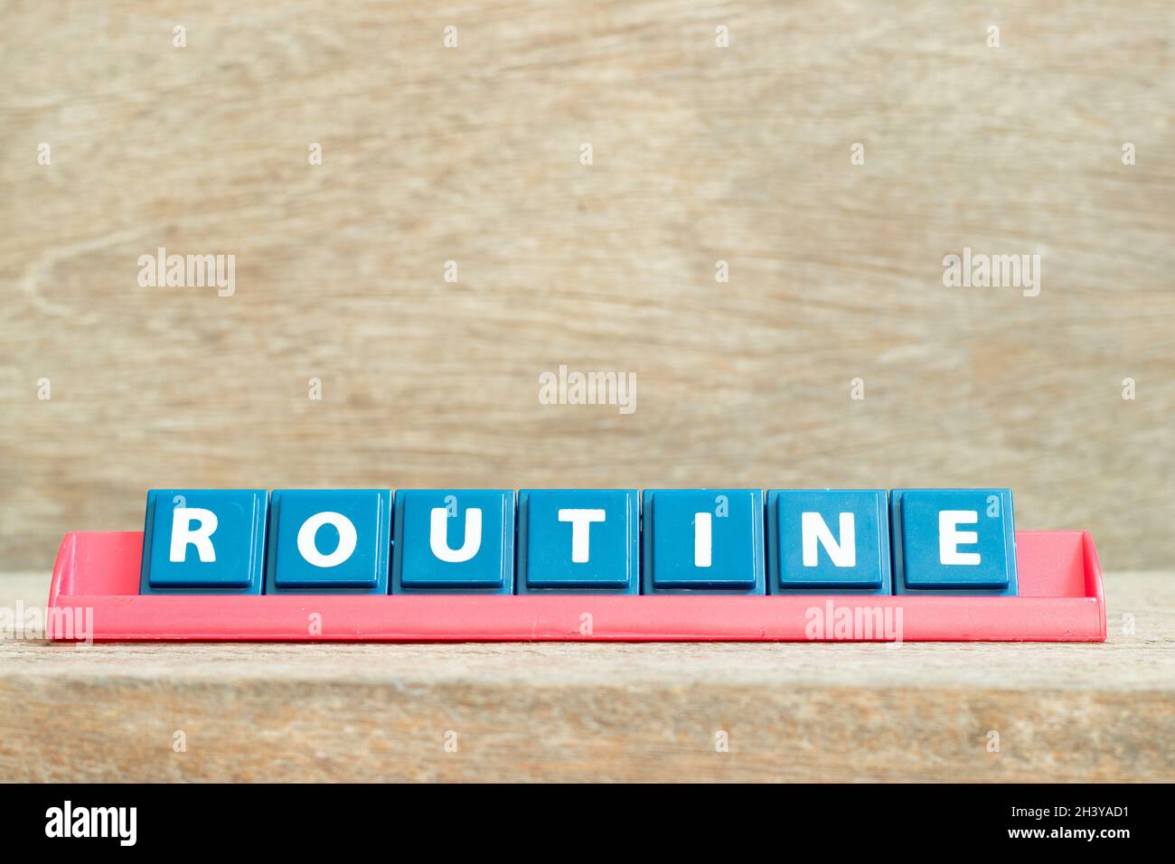 Tile alphabet letter with word routine in red color rack on wood ...
