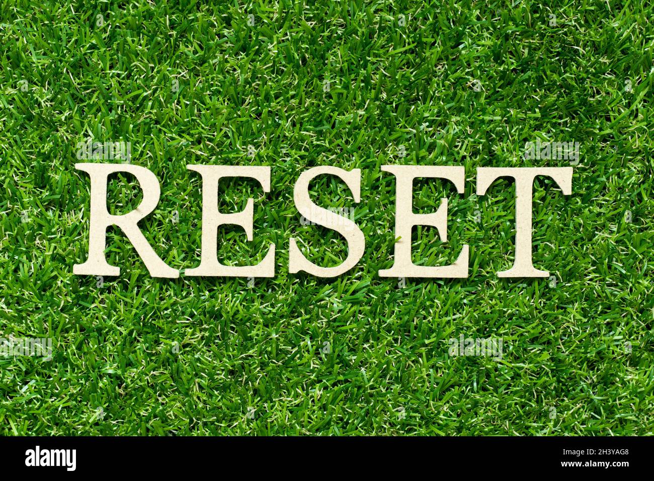 Wood letter in word reset on green grass background Stock Photo - Alamy