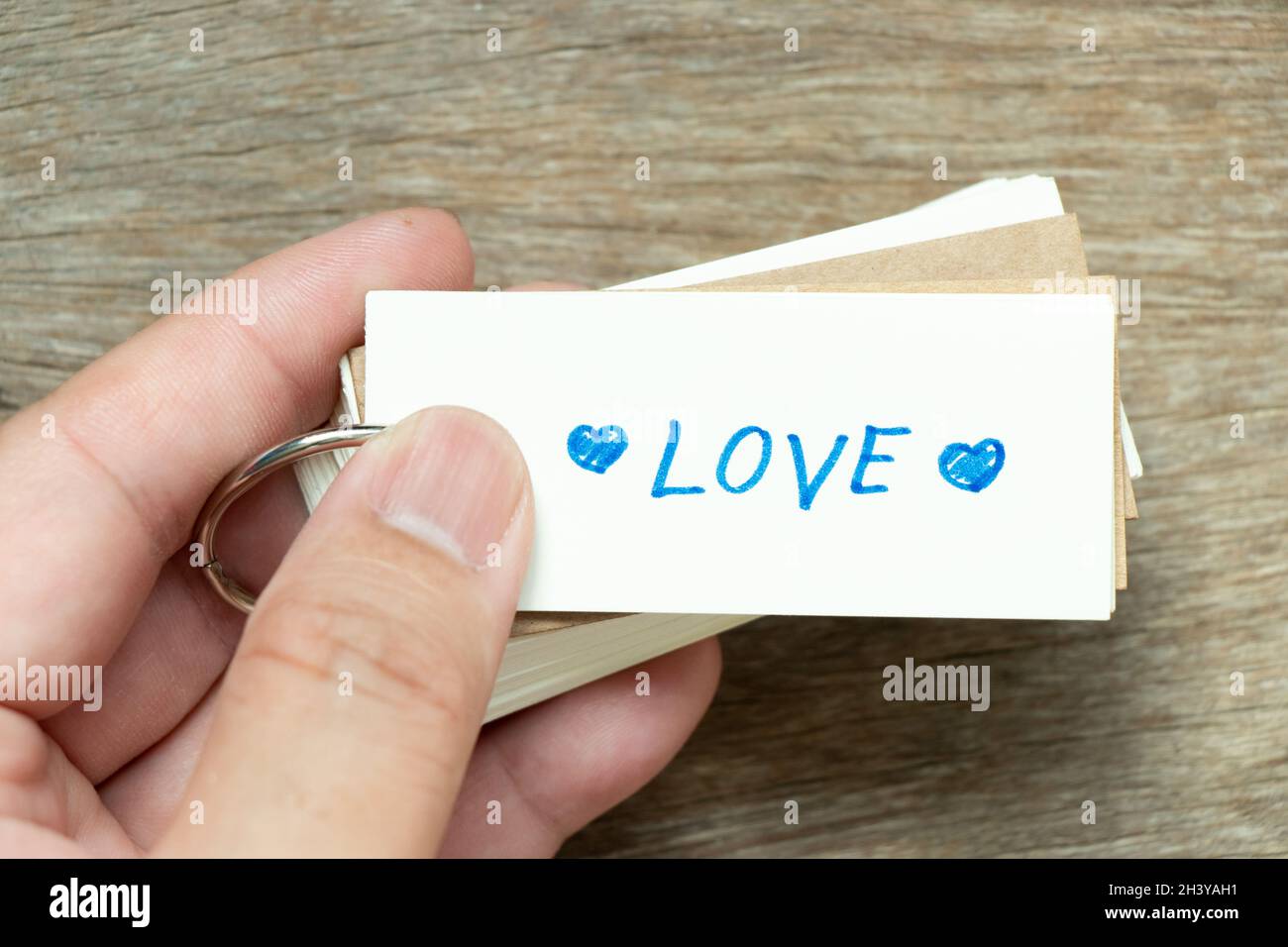 Man hold the flash card with handwriting word love on wood background ...