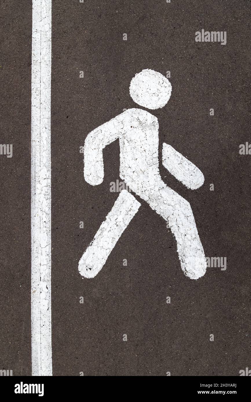 White walking person street sign on grey city asphalt road with ...