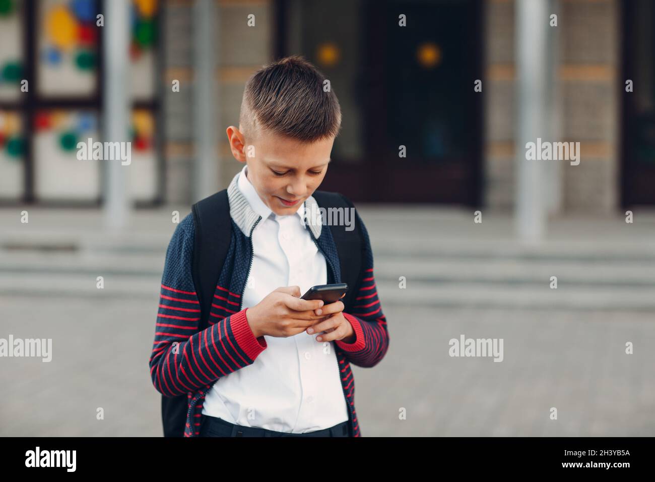 Schoolboy teenager boy with mobile phone standing at school on ...