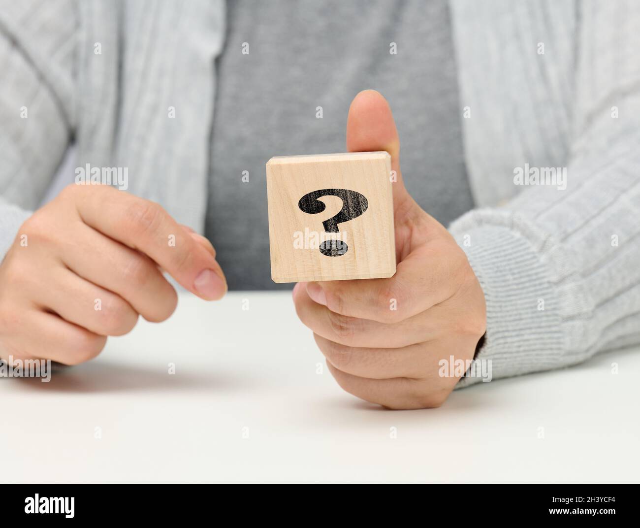Female hand holding a wooden cube with a question mark, concept of ...