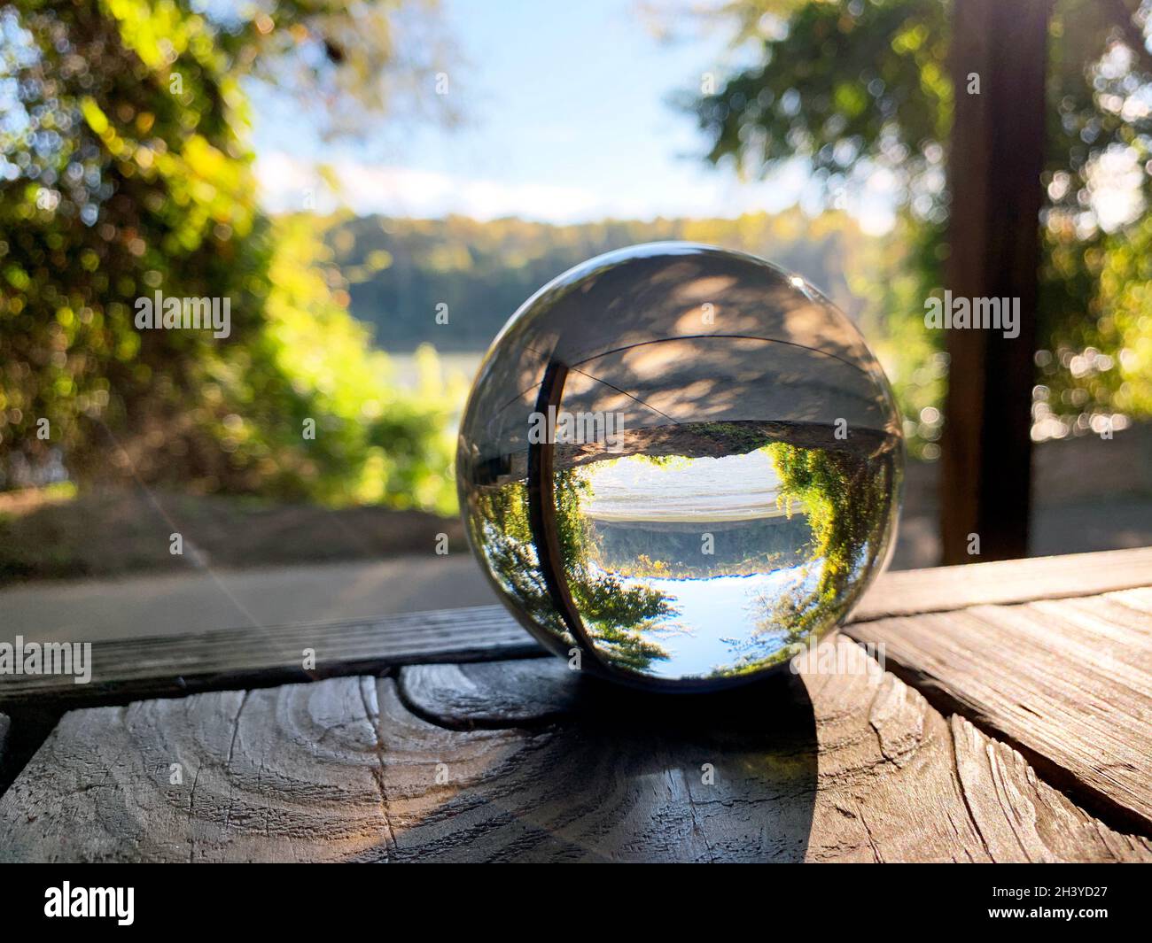 Inverted river seen through glass ball on wood table in early morning ...