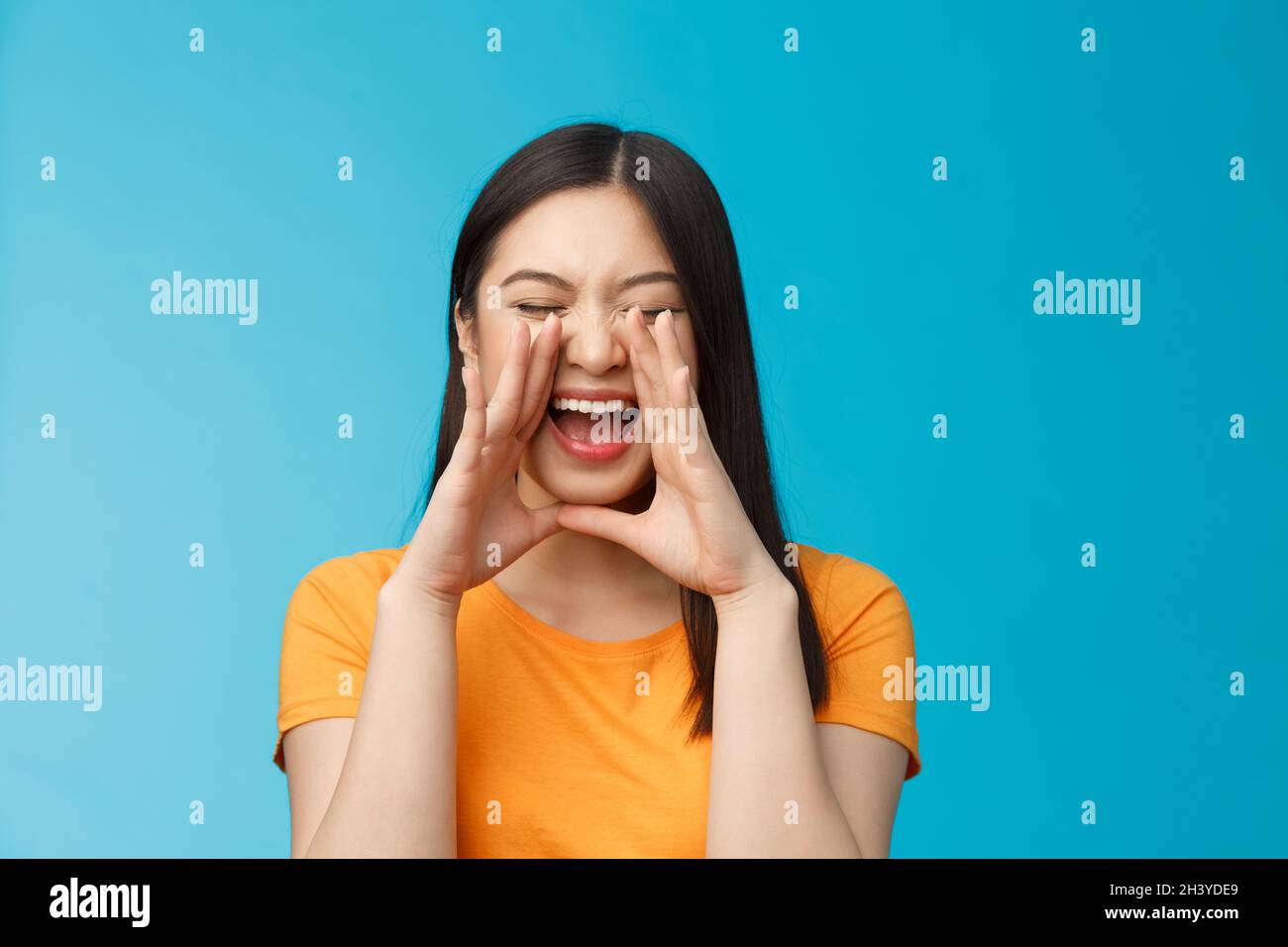Carefree asian enthusiastic girl shouting long distance, calling friend ...