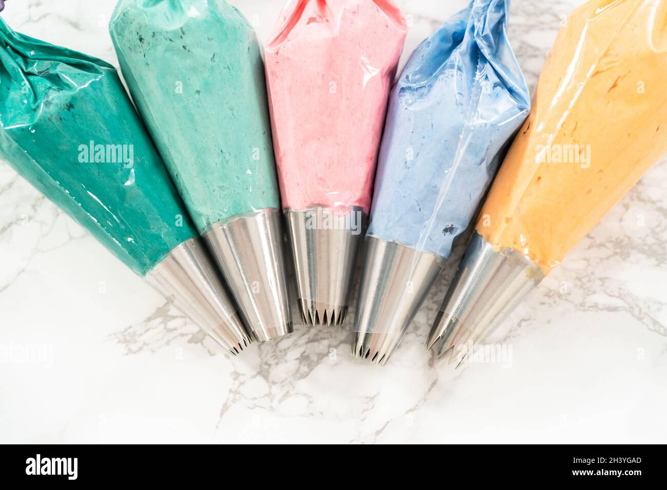 Piping bag with metal tips filled with colorful Italian buttercream ...