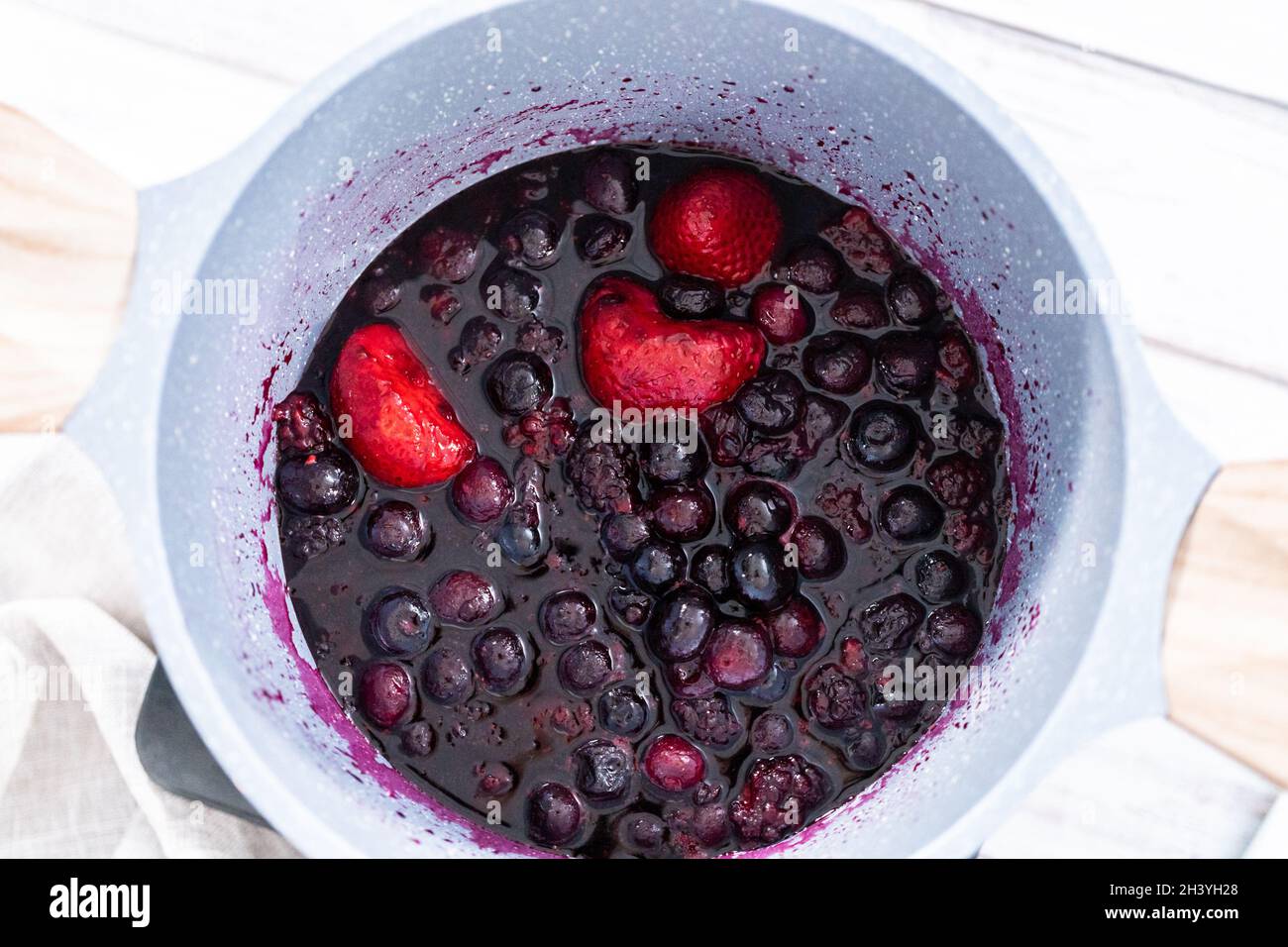 Preparing mixed berry compote from frozen berries in a nonstick cooking ...