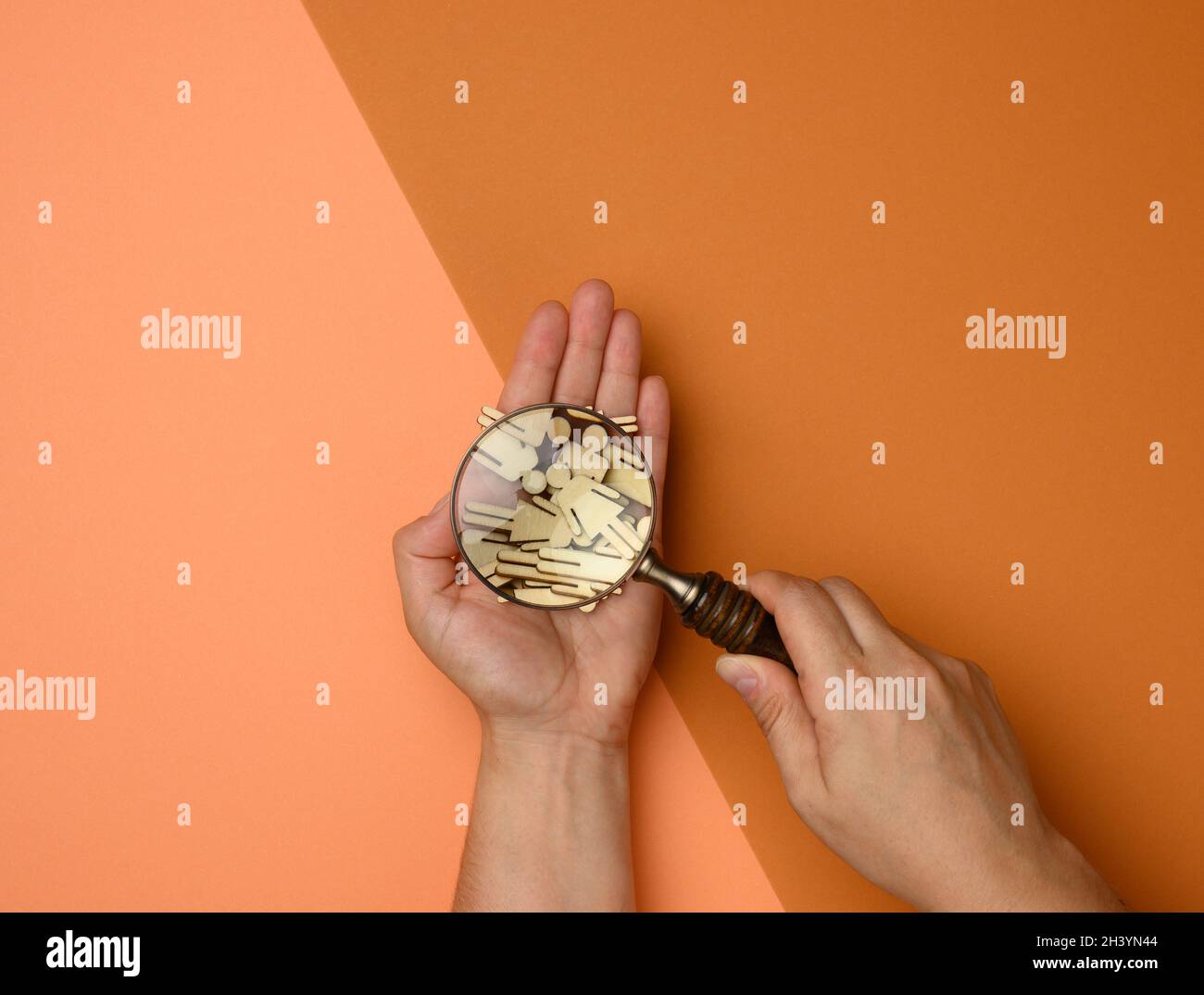Wooden men and a magnifying glass on a brown background. Recruitment ...