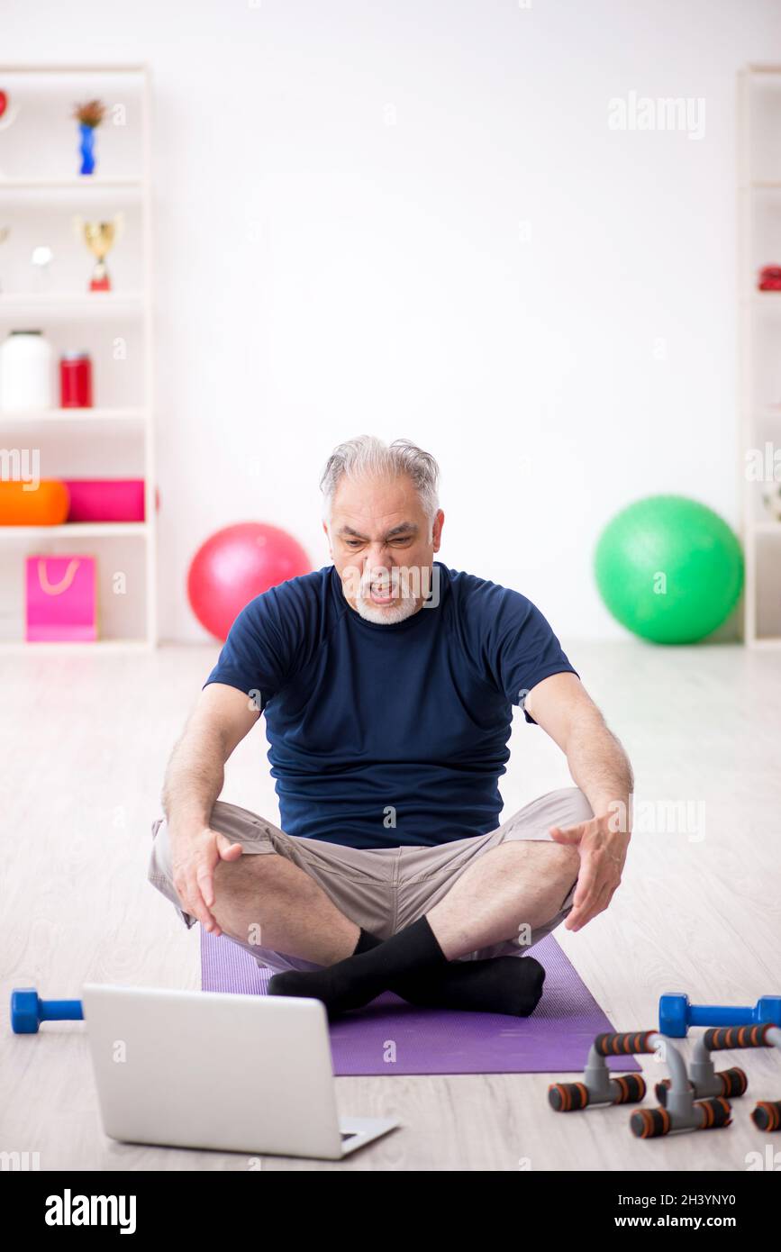 Old man doing sport exercises indoors Stock Photo - Alamy