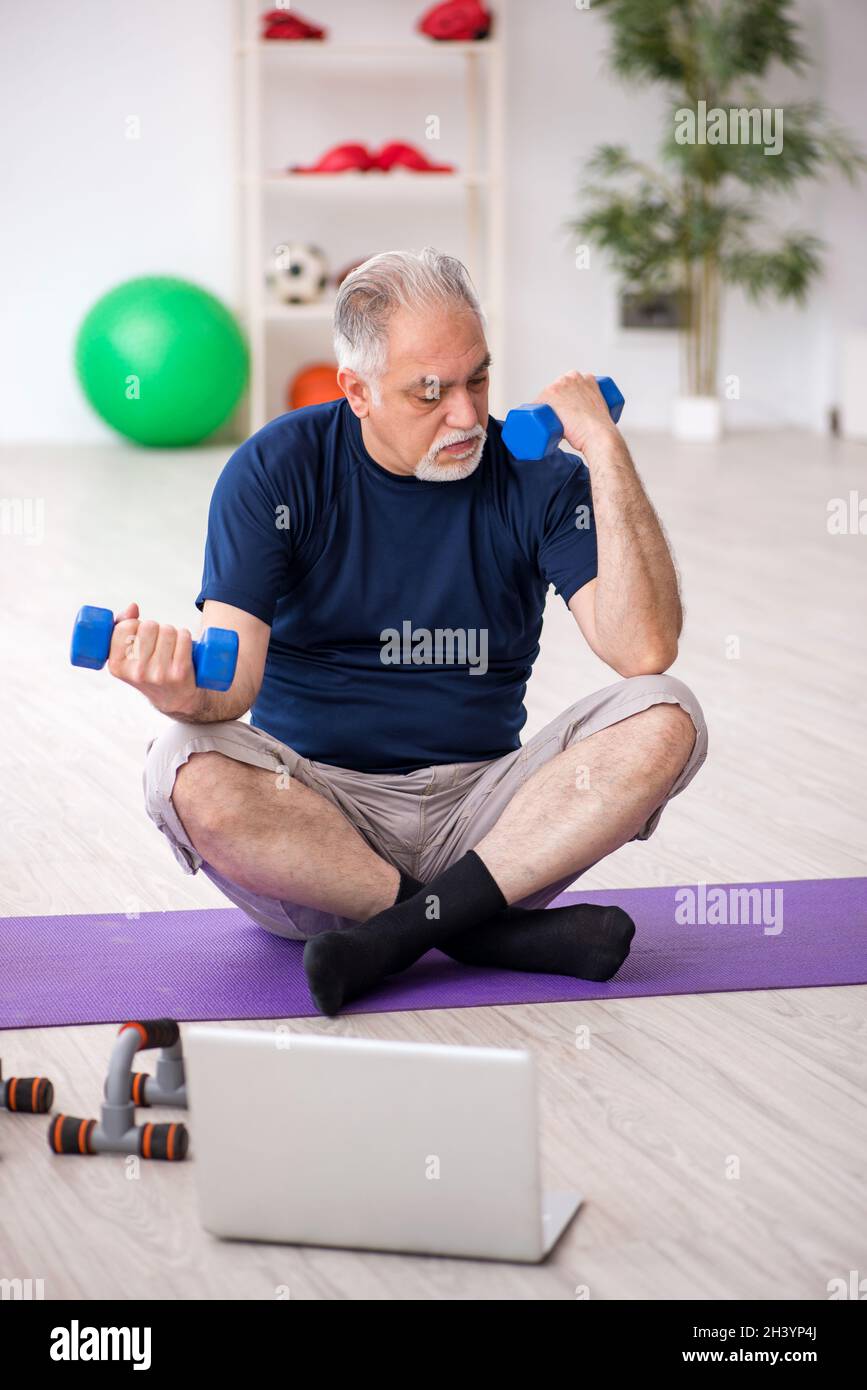 Old man doing sport exercises indoors Stock Photo - Alamy