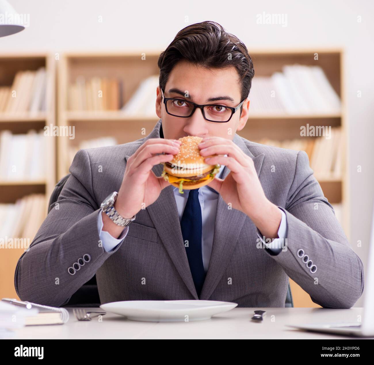 Hungry funny businessman eating junk food sandwich Stock Photo - Alamy