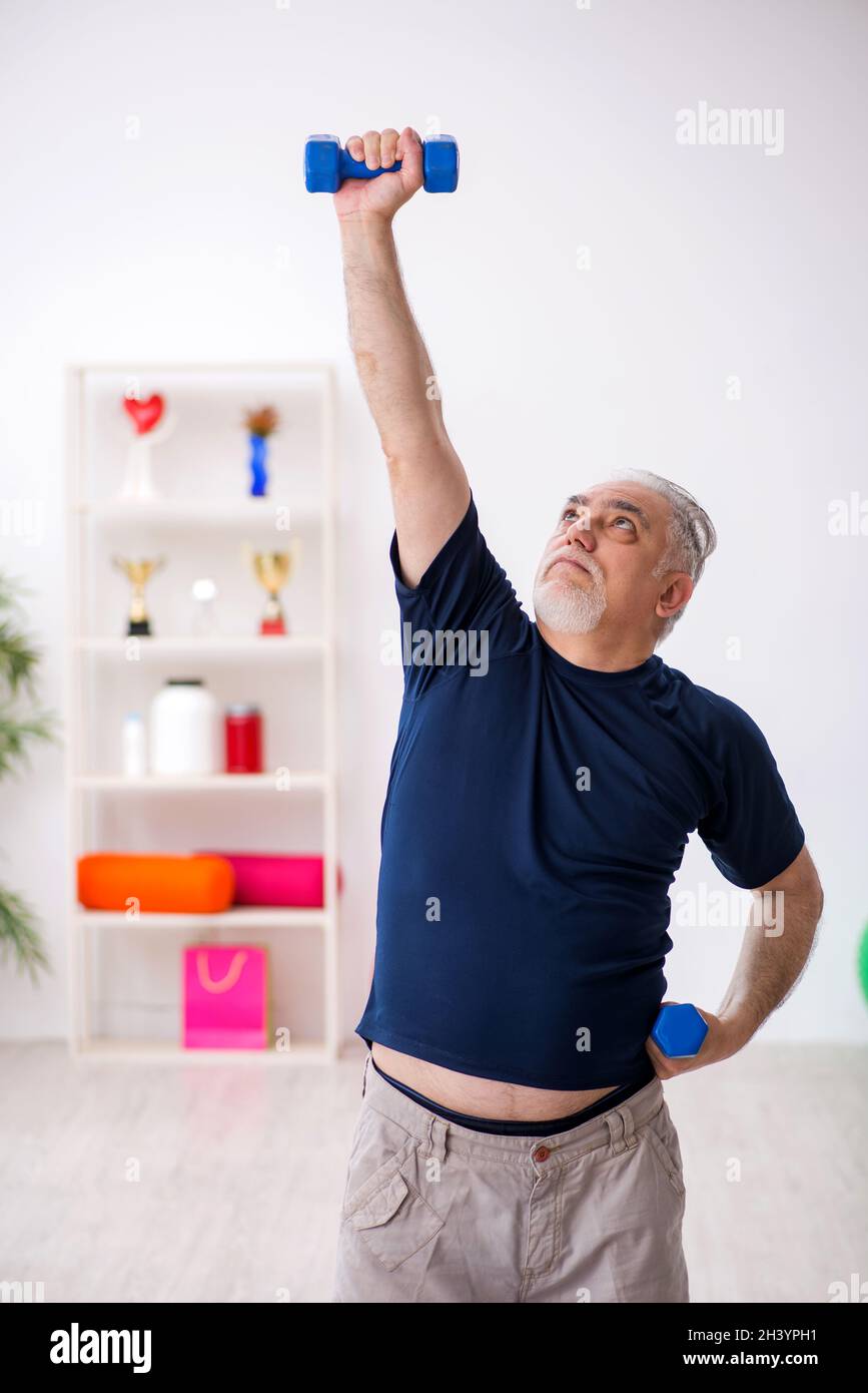 Old man doing sport exercises indoors Stock Photo - Alamy