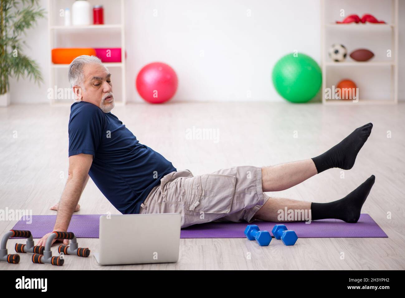 Old man doing sport exercises indoors Stock Photo - Alamy
