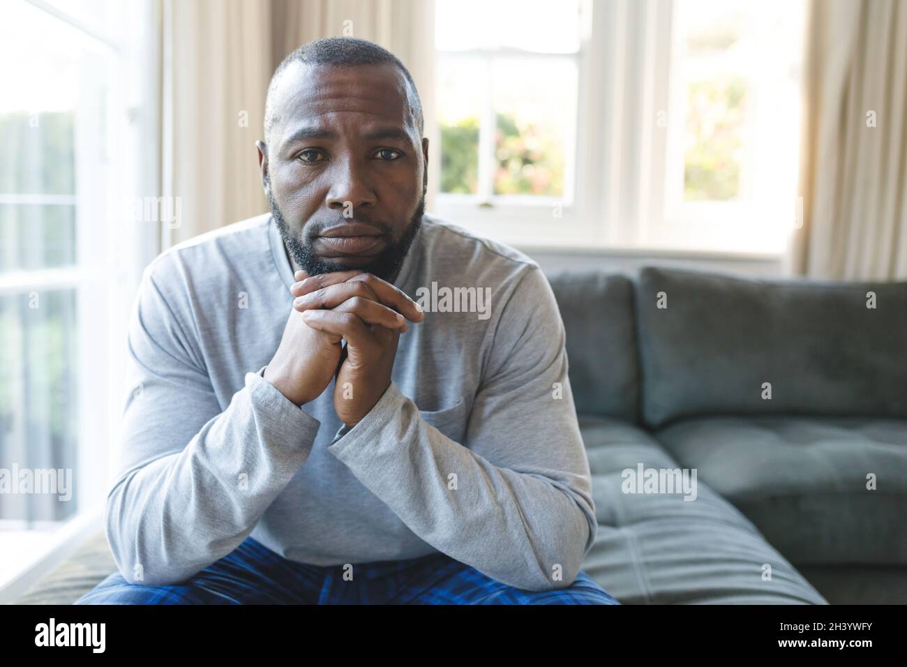 Portrait of sad african american man thinking and sitting with chin on ...