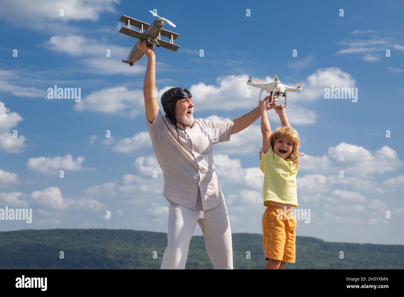 Grandfather and son with plane and quadcopter drone over blue sky and ...