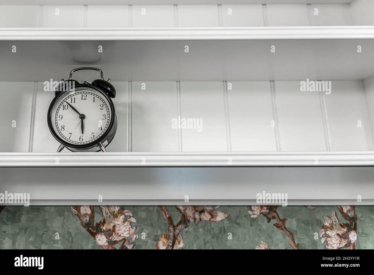 Classic vintage alarm clock on the shelf in the interior of the room ...