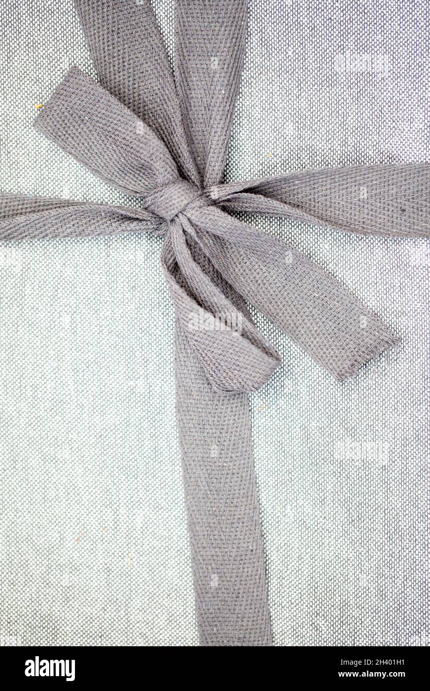 Close up cute grey ribbon bow on a grey linnen package Stock Photo - Alamy