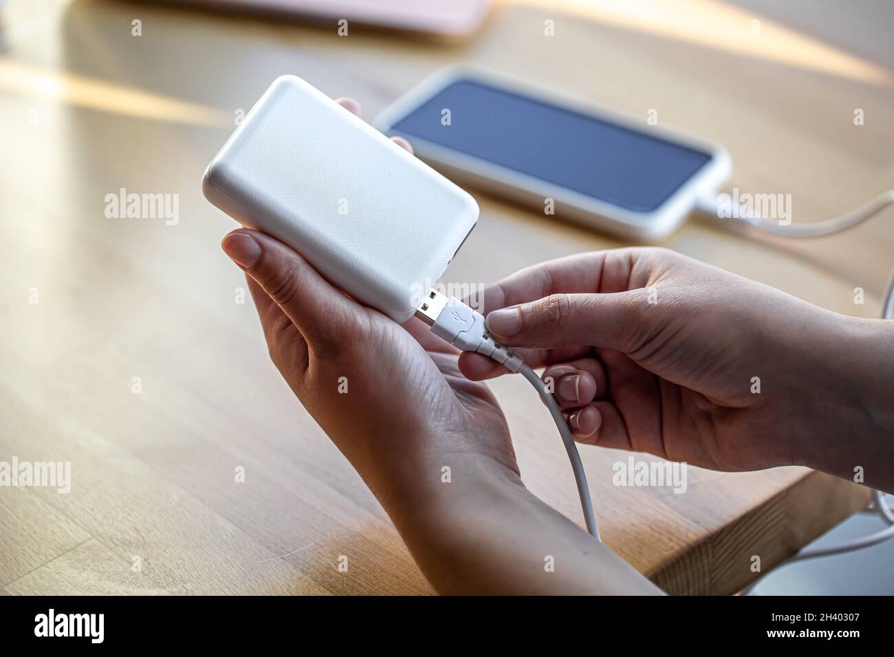 Woman's hand holding white USB cable and white power bank Stock Photo ...