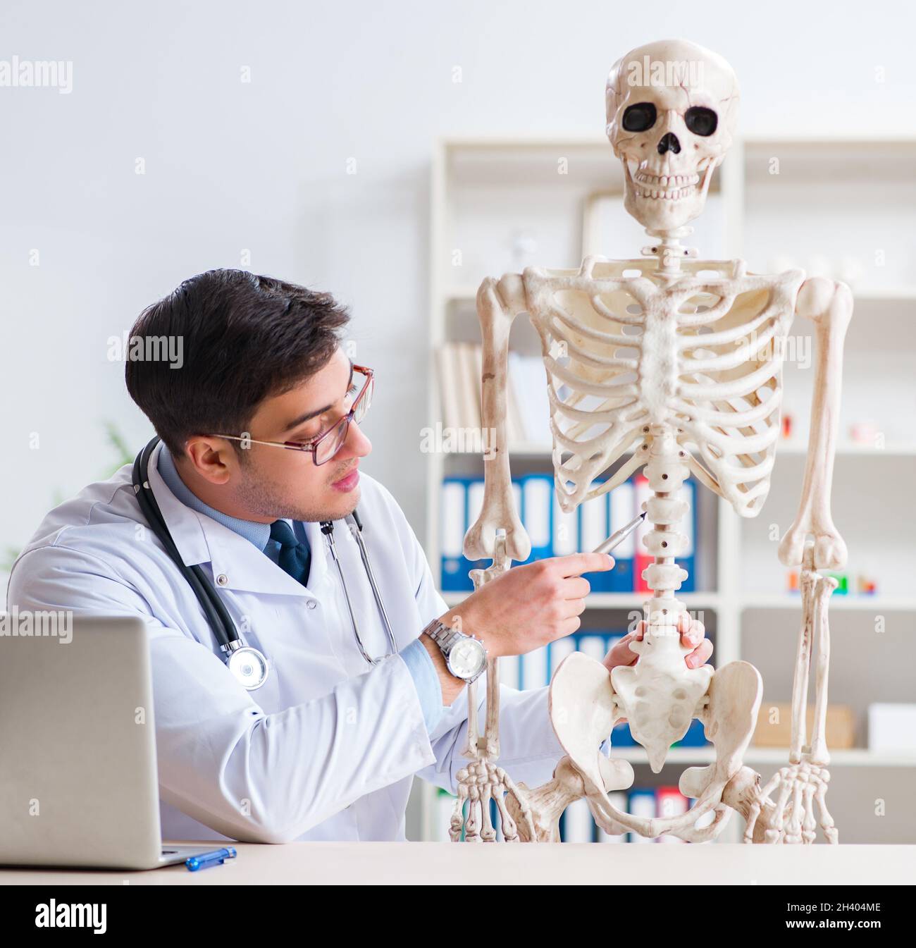 Yong male doctor with skeleton isolated on white Stock Photo - Alamy