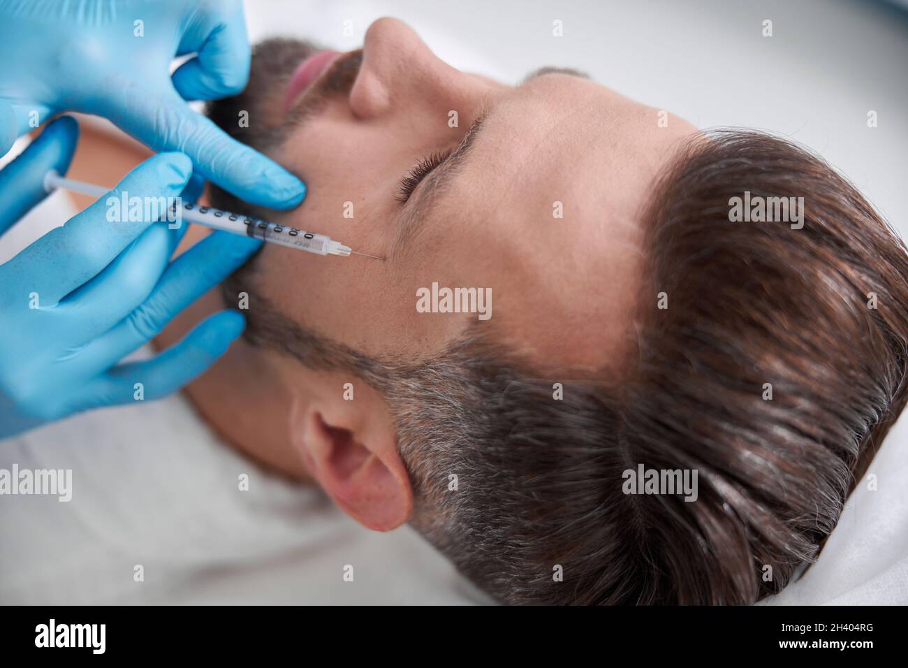 Skilled beautician does filler injection for crows feet to middle aged ...