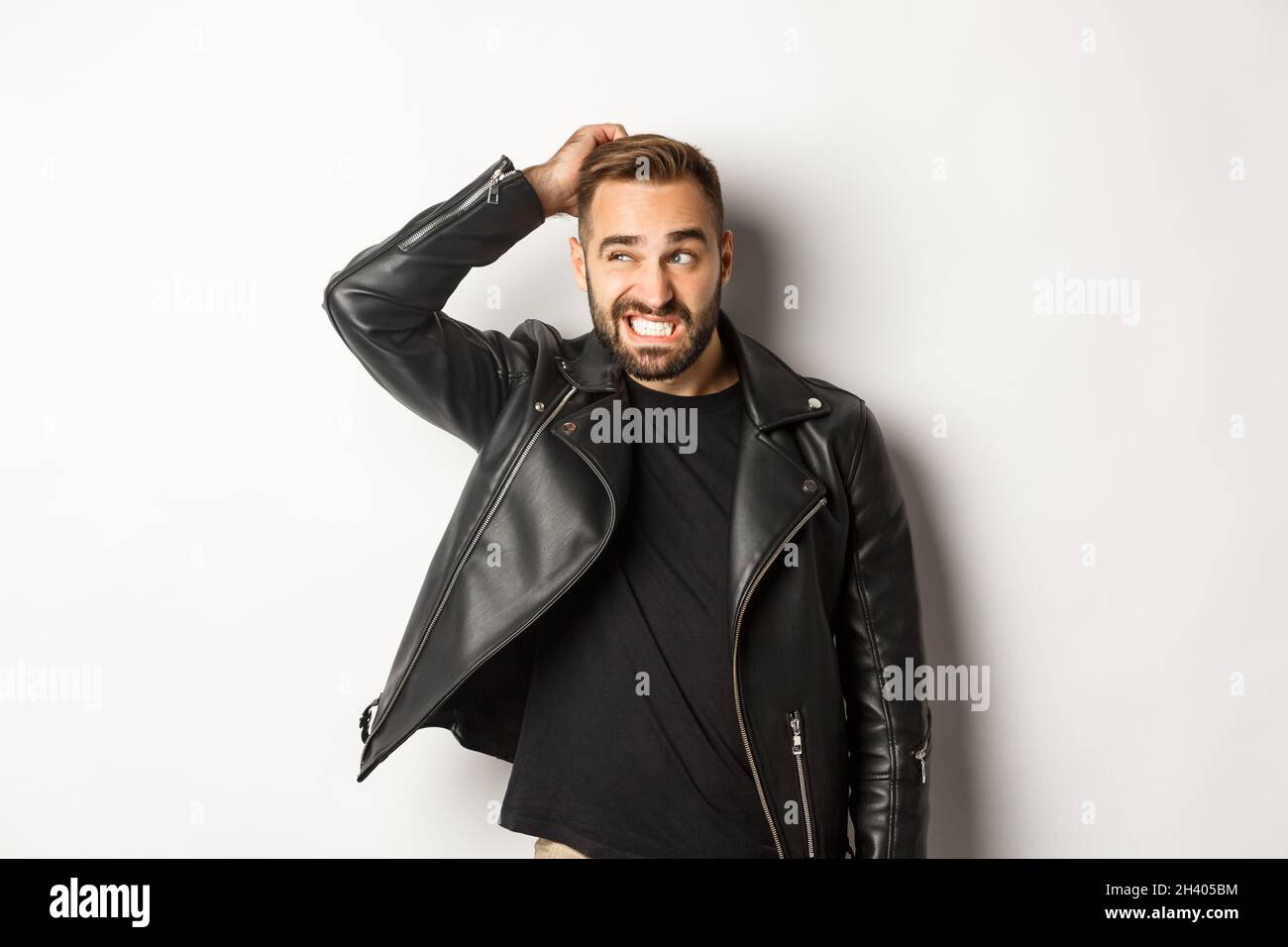 Confused macho guy in black leather jacket looking awkward and unsure ...
