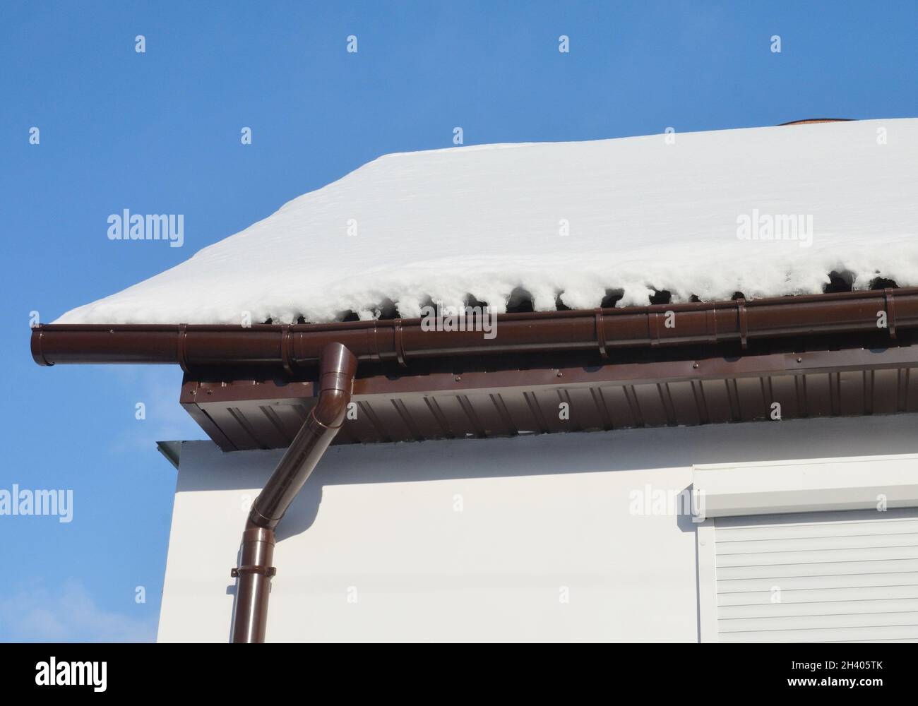A rooftop and rain gutter covered with snow and ice in winter Stock ...
