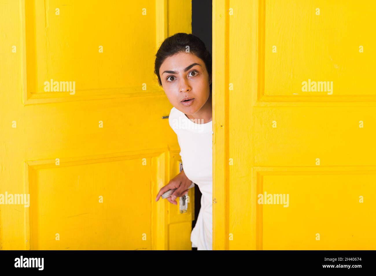 Woman peeking through door hi-res stock photography and images - Alamy