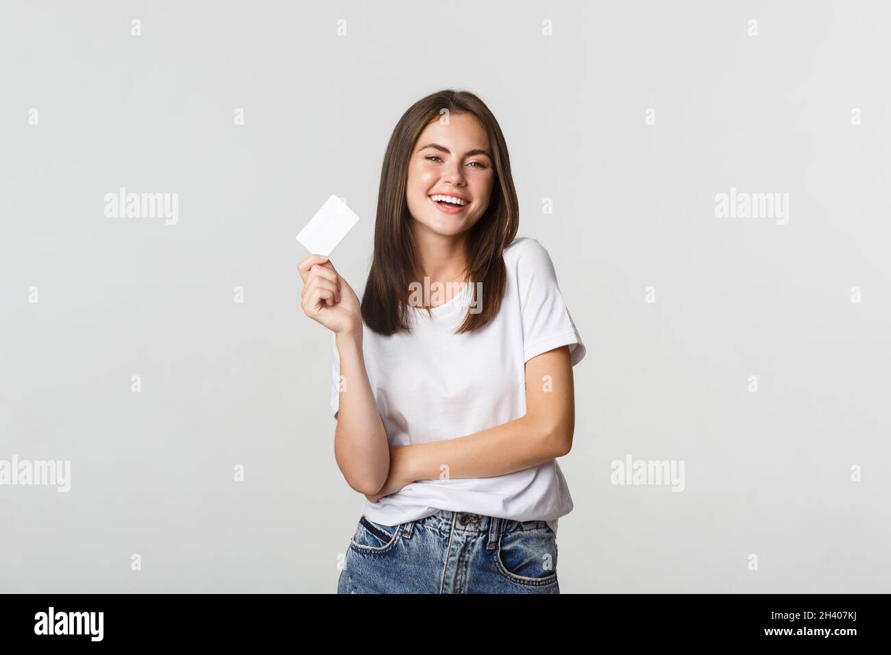 Attractive happy brunette girl laughing and holding credit card, white ...