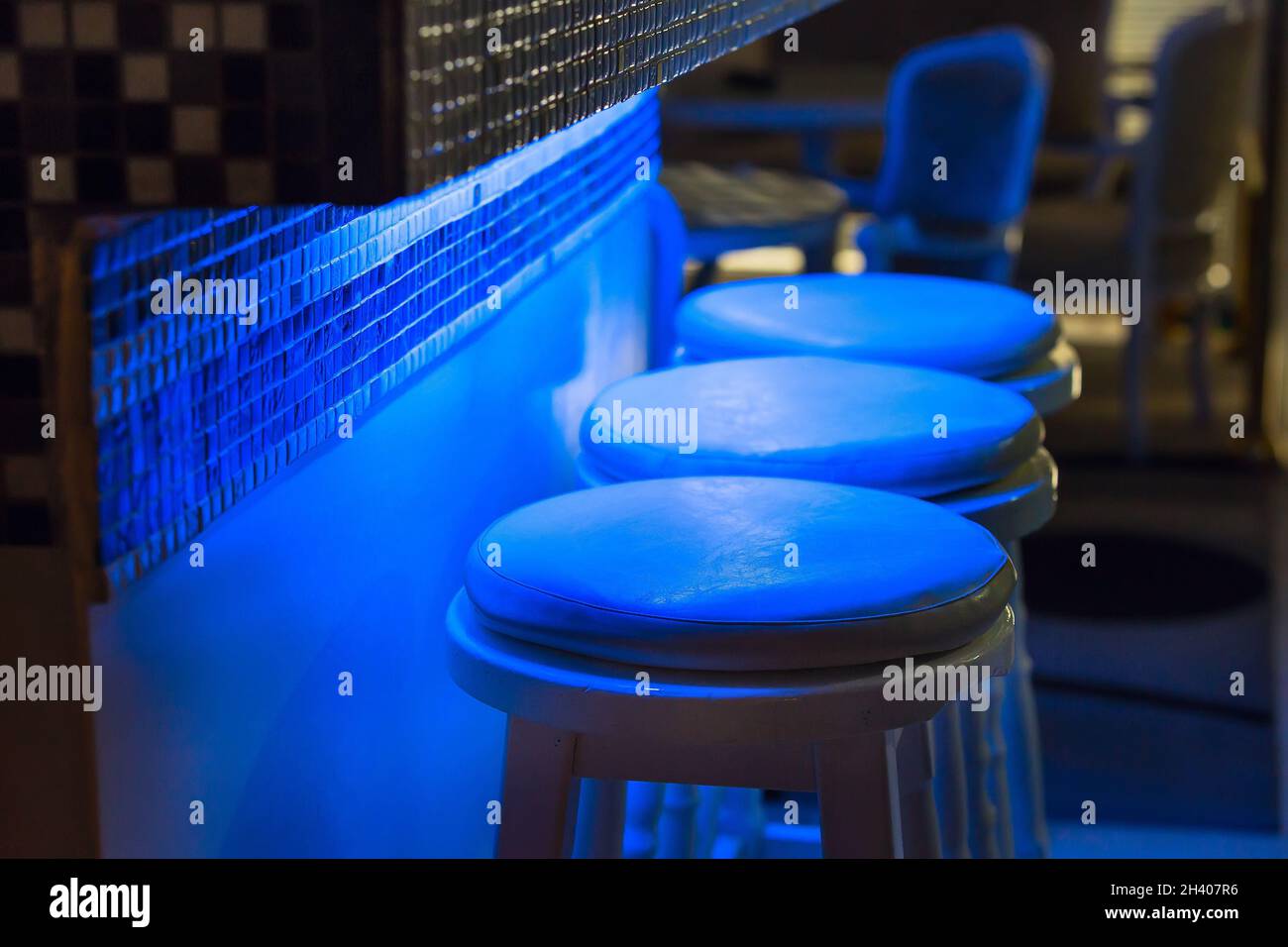 Empty stools along bar Illuminated in blue light Stock Photo - Alamy
