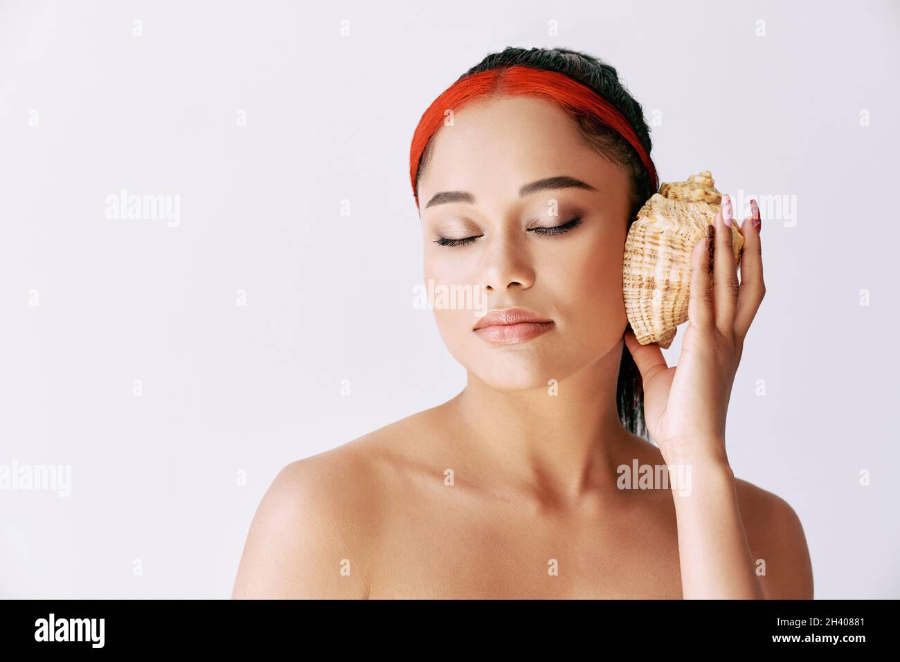 Pretty afro woman with closed eyes pressed seashell to her ear enjoy ...