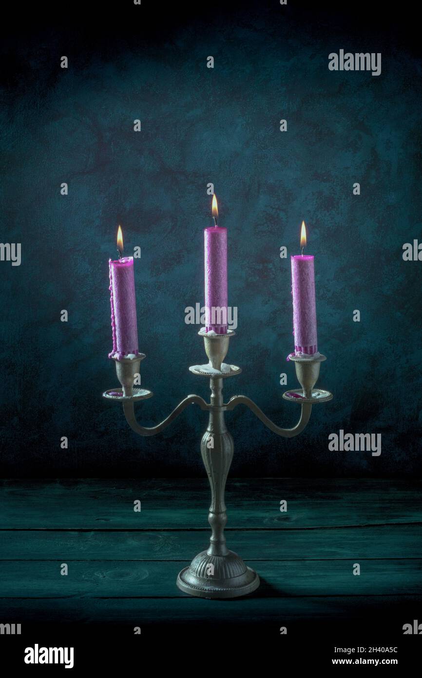 Magic candles in a vintage candle holder, side view on a dark ...